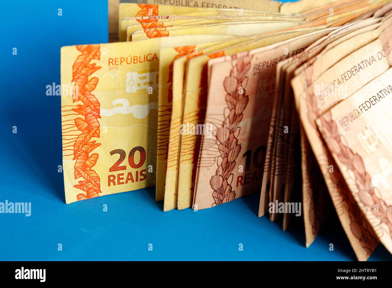 several Brazilian real banknotes lined up on a blue table - emphasis on ...