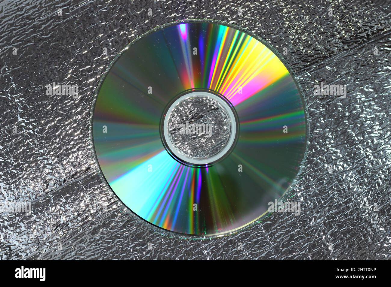 Closeup of a compact disk with colorful glare on a flat surface with ...
