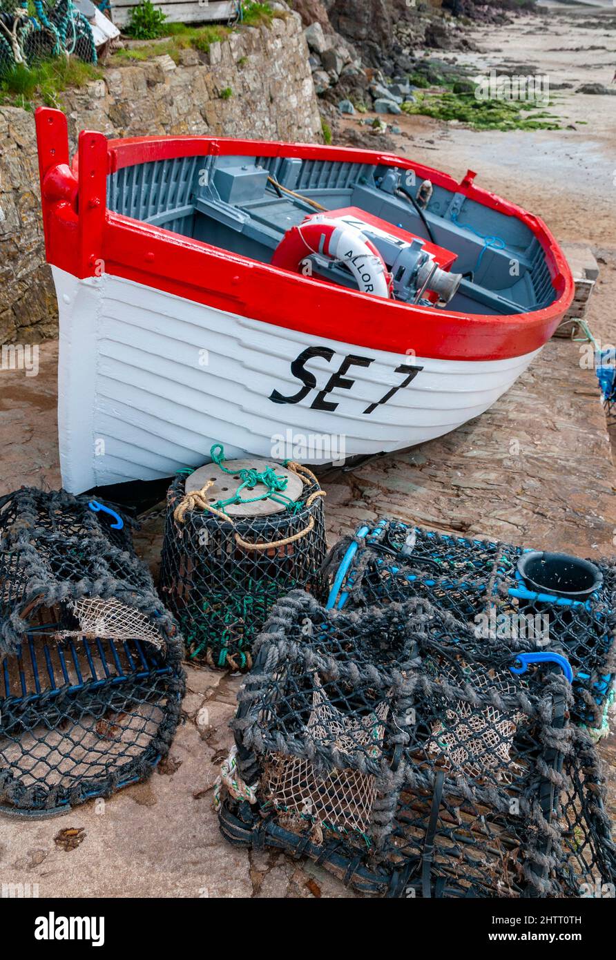 Fishing boat with lobster pots pulled up on the slipway at the sandy ...