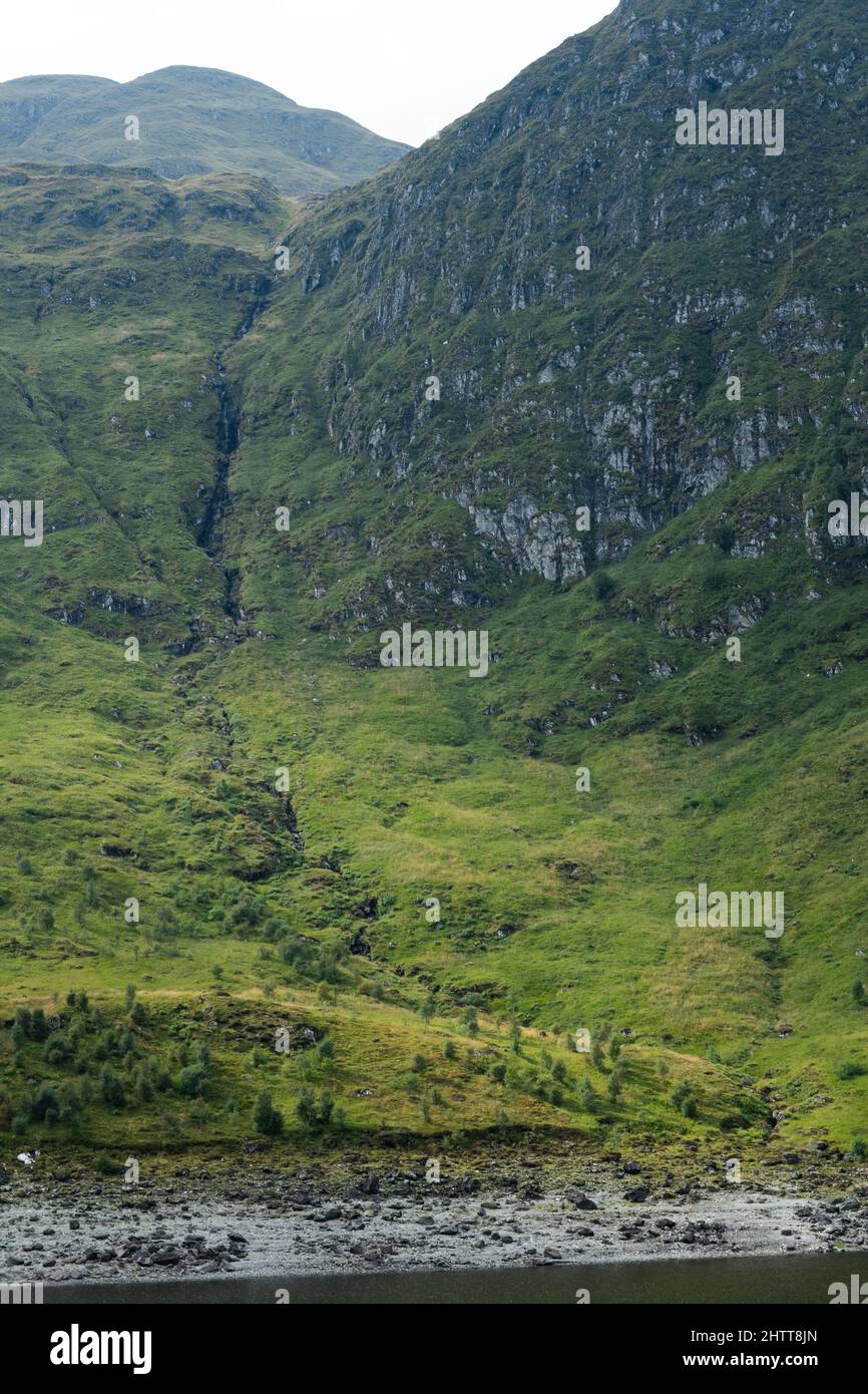 A view over Lochan na Lairige to a mountain ridge and a waterfall ...
