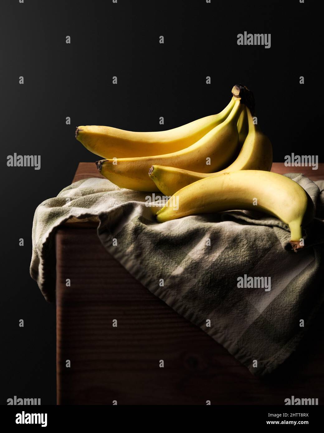 Vertical still life of bananas on a black background Stock Photo - Alamy