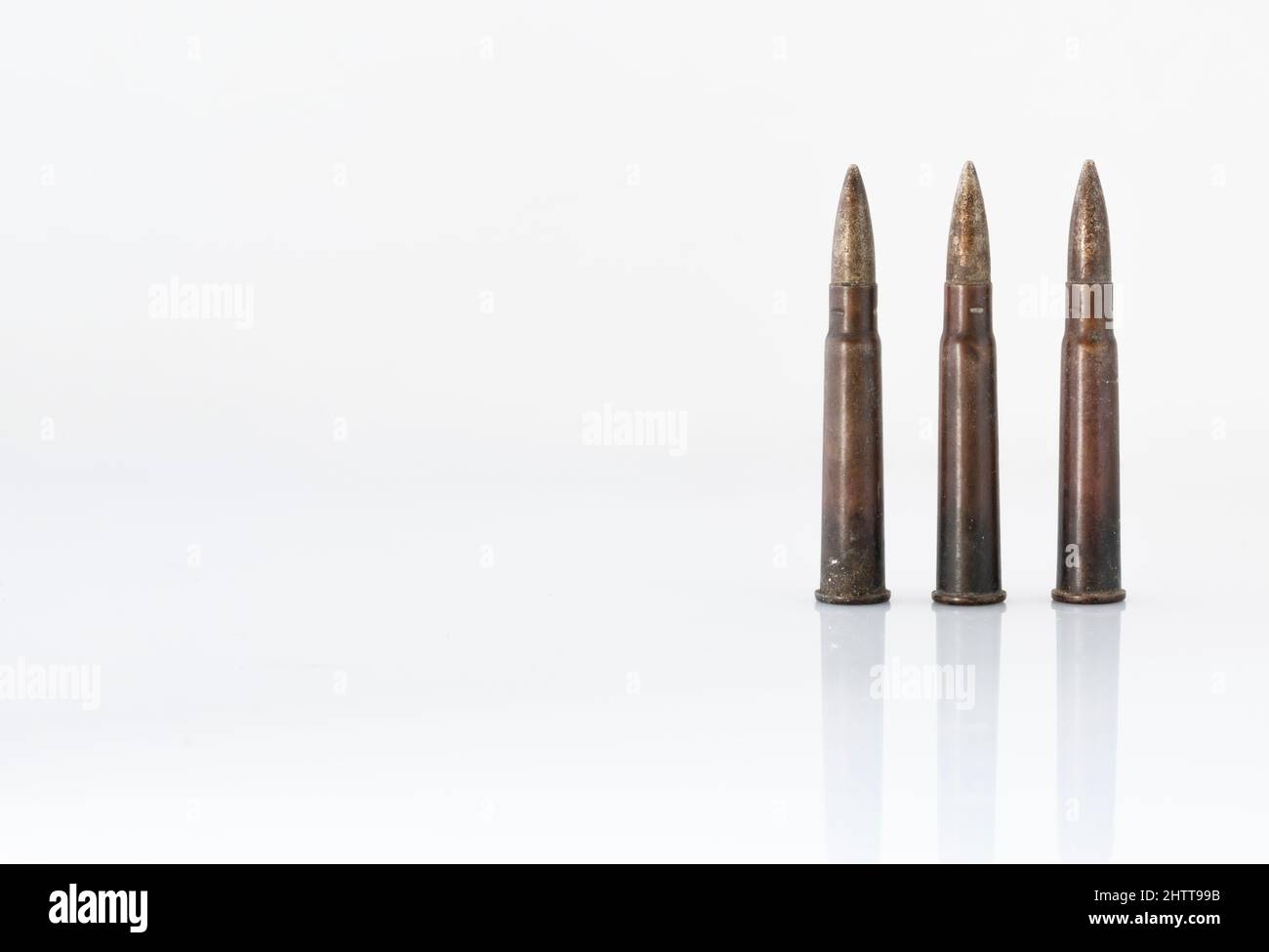 brass bullets photographed on a reflective white base and a white ...