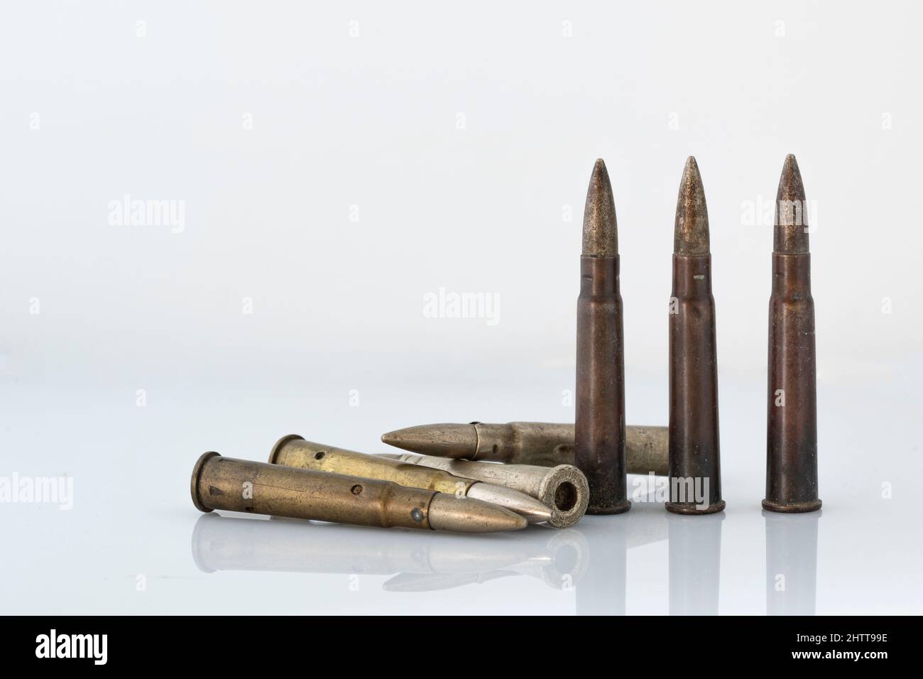 brass bullets photographed on a reflective white base and a white ...