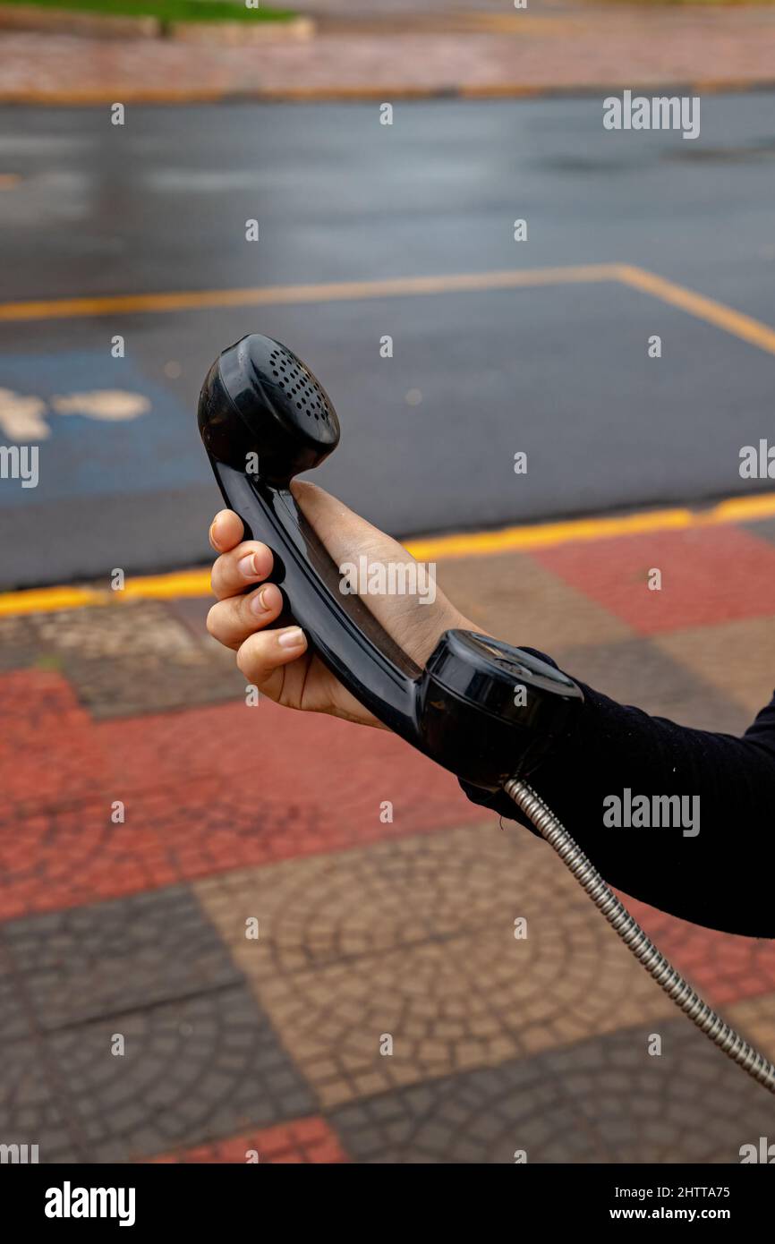 black telephone of a public payphone being held by a woman Stock Photo ...
