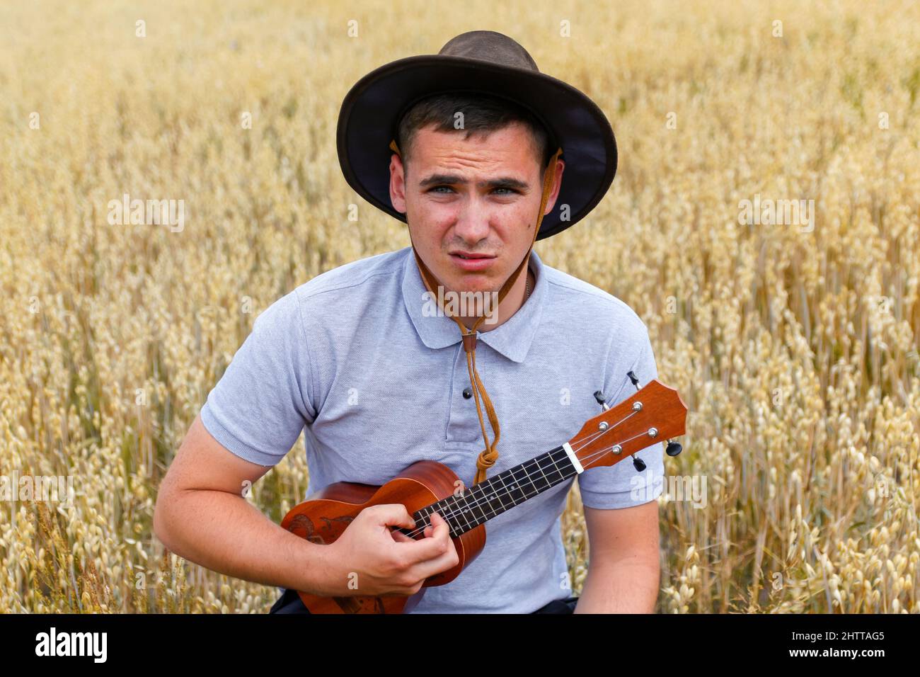 Sad person. Young beautiful caucasian man playing ukulele outside ...