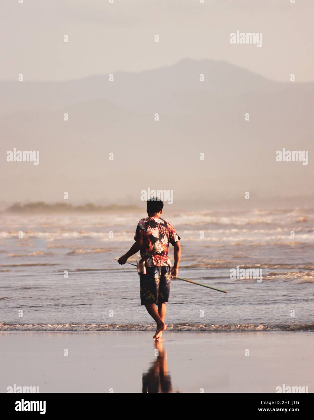 Vertical shot of a young guy trying to catch a fish with a stick Stock ...
