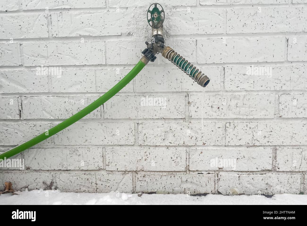 Closeup of a Frozen outdoor water spigot on white brick wall background ...