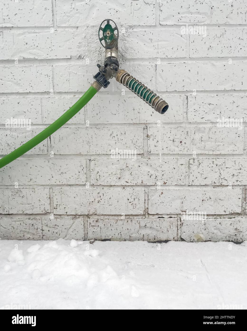 Closeup of a Frozen outdoor water spigot on white brick wall background ...