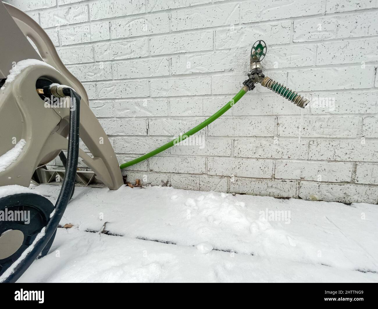Closeup of a Frozen outdoor water spigot on white brick wall background ...