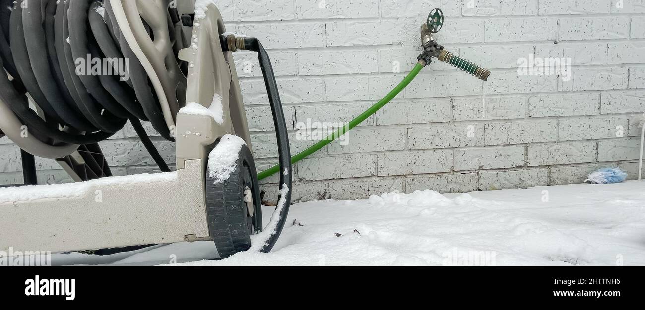 Closeup of a Frozen outdoor water spigot on white brick wall background ...