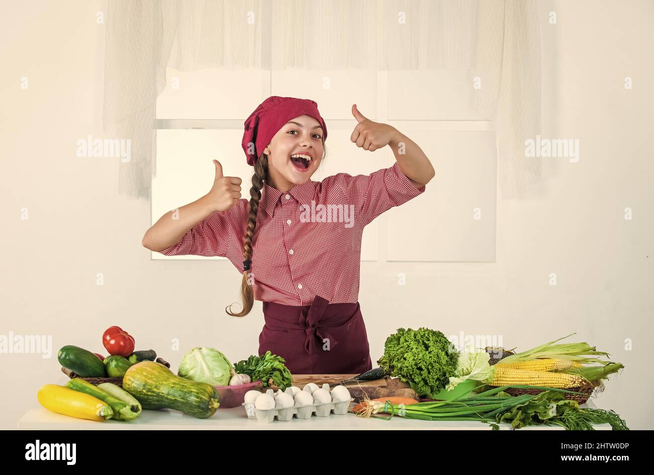 smiling teen girl in chef uniform cooking vegetables, grocery Stock ...