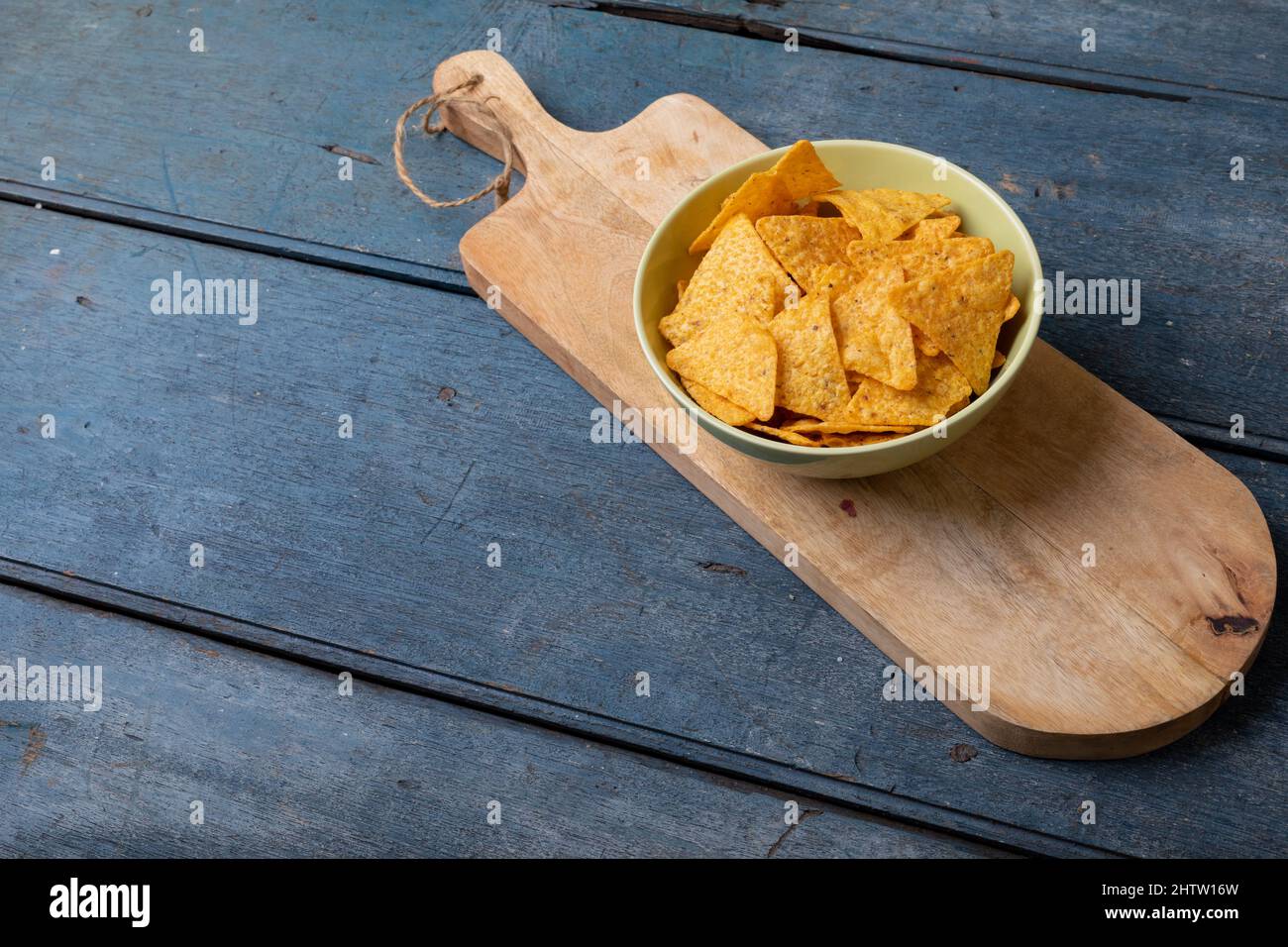 High angle view of nacho chips in bowl on serving board at wooden table ...