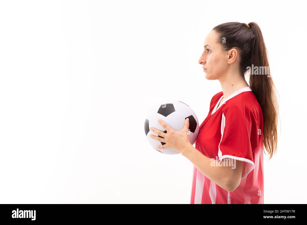 Side view of caucasian young female player with soccer ball standing ...