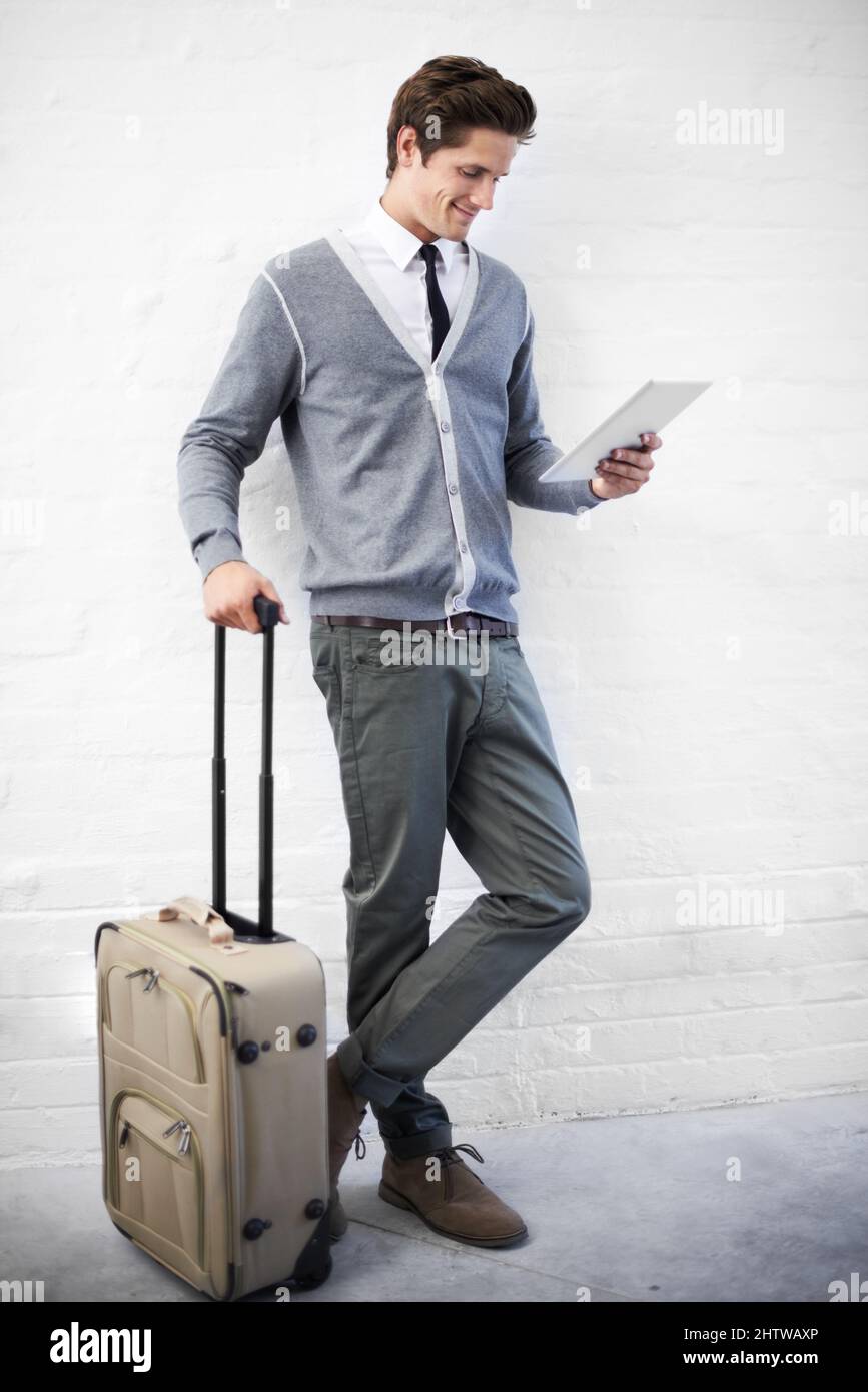 Booking a flight online. A handsome young nerd with luggage working on ...