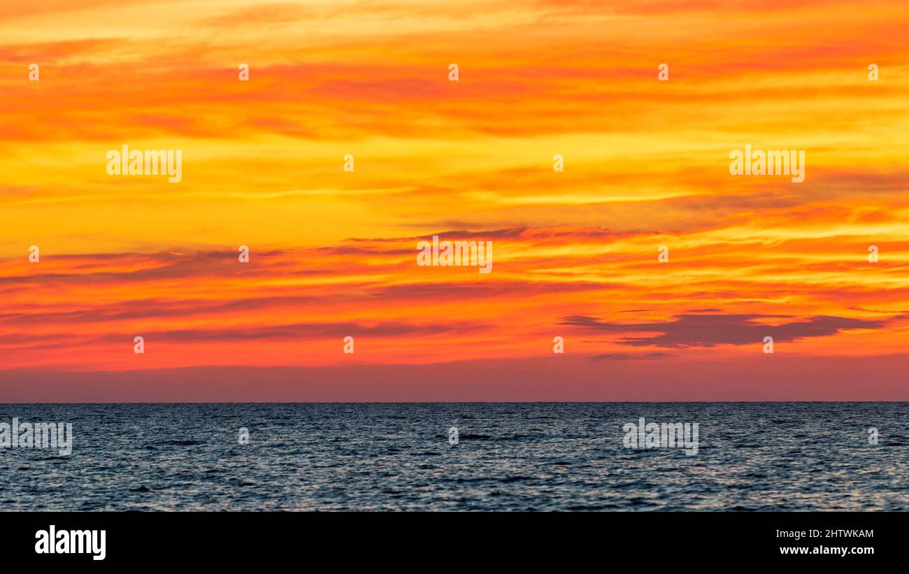 vibrant orange sunset sky and clouds over ocean Stock Photo - Alamy