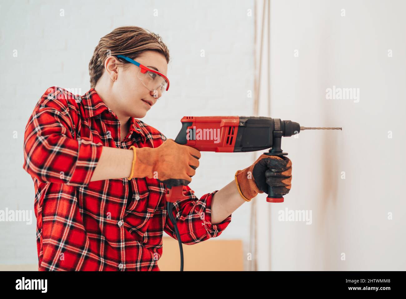 Laborer girl drilling concrete wall with drill Stock Photo - Alamy