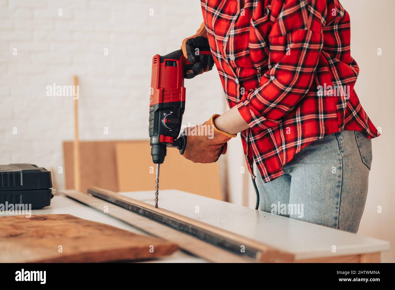 Laborer girl drilling plank with drill on the table Stock Photo - Alamy