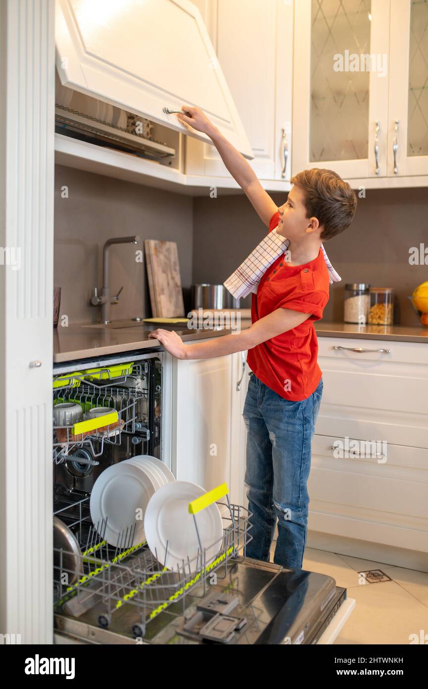 Joyous kid looking at dishware arranged on the dish drainer Stock Photo ...