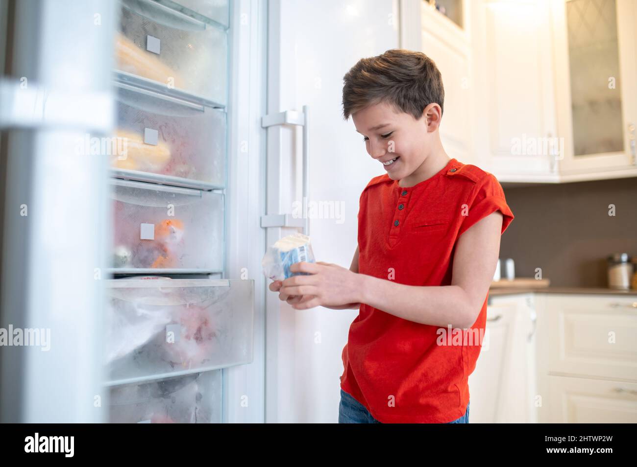Joyous kid selecting frozen products from the fridge Stock Photo - Alamy