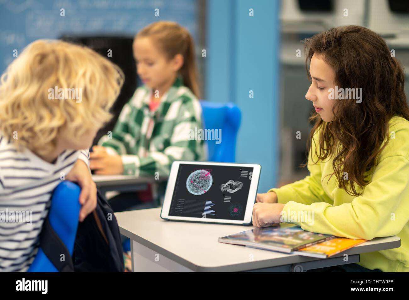 Girl showing tablet screen with educational information to boy Stock ...