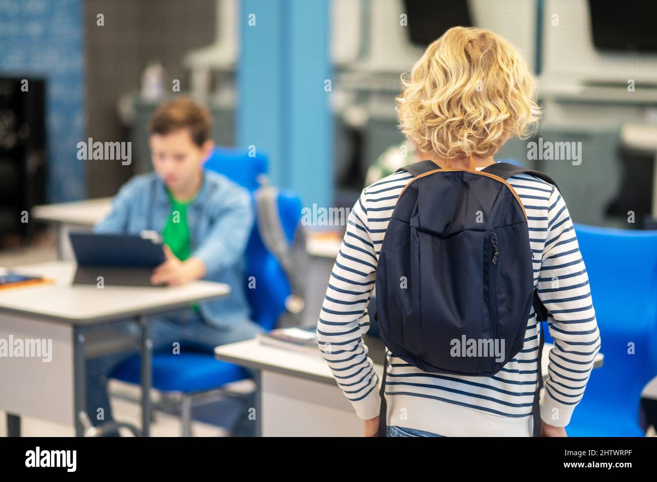 Boy standing with back to camera in classroom Stock Photo - Alamy