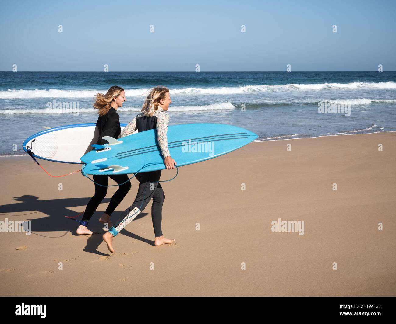 2 surfer women running with surfboards on the beach shore Stock Photo ...