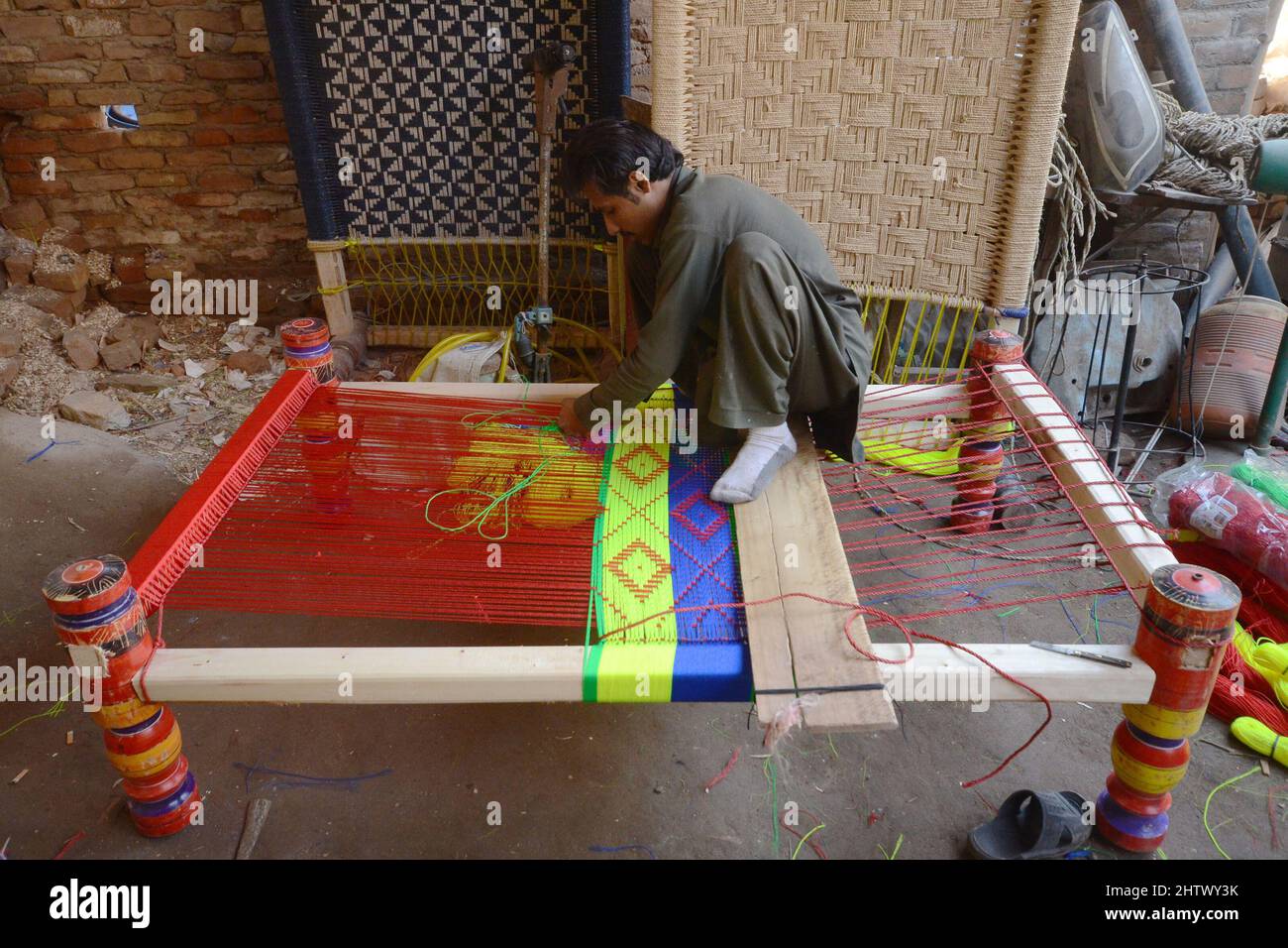Peshawar. 2nd Mar, 2022. A worker knits a traditional bed locally ...