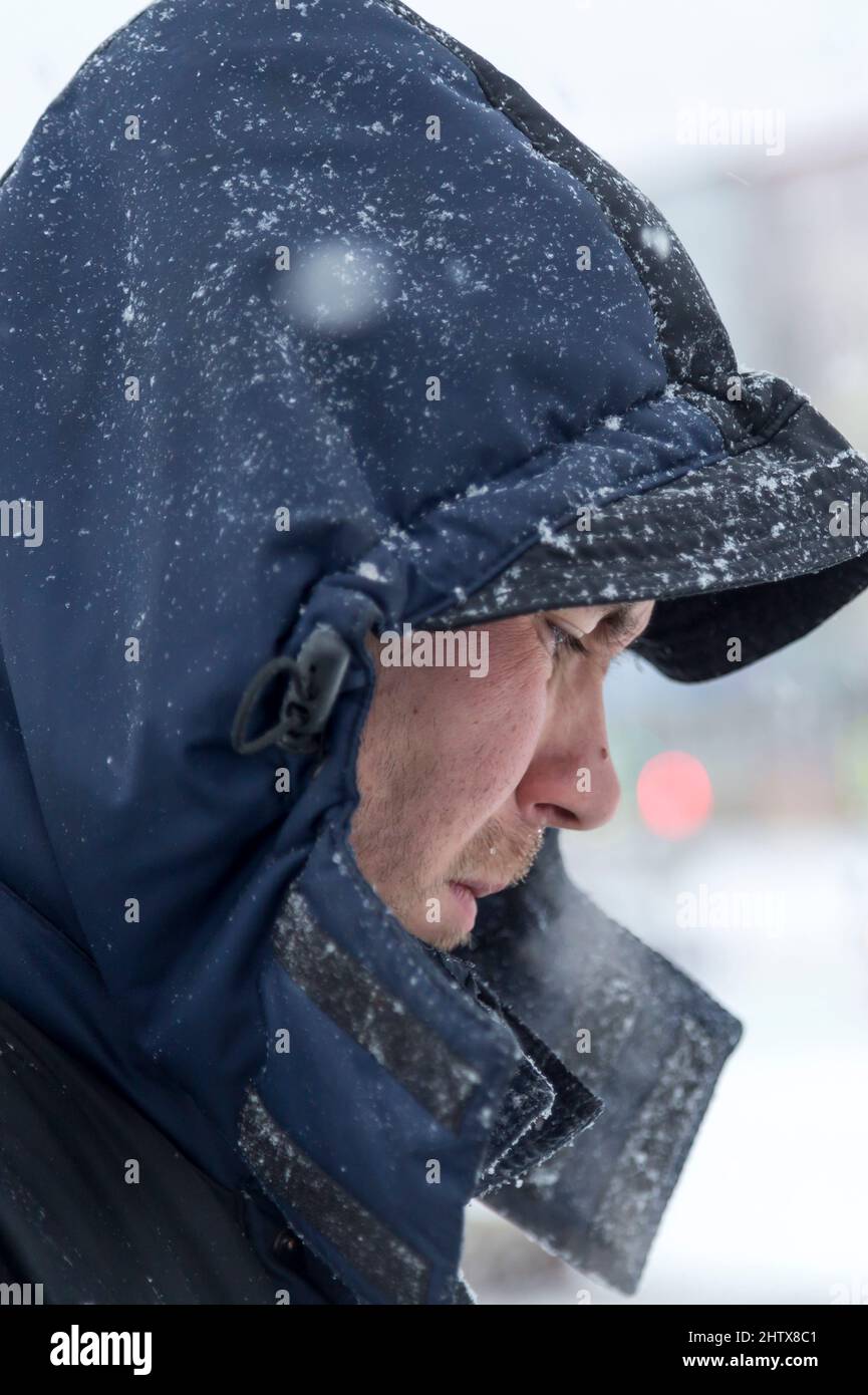 Portrait of a worker in a blue hooded jacket in profile at the ...