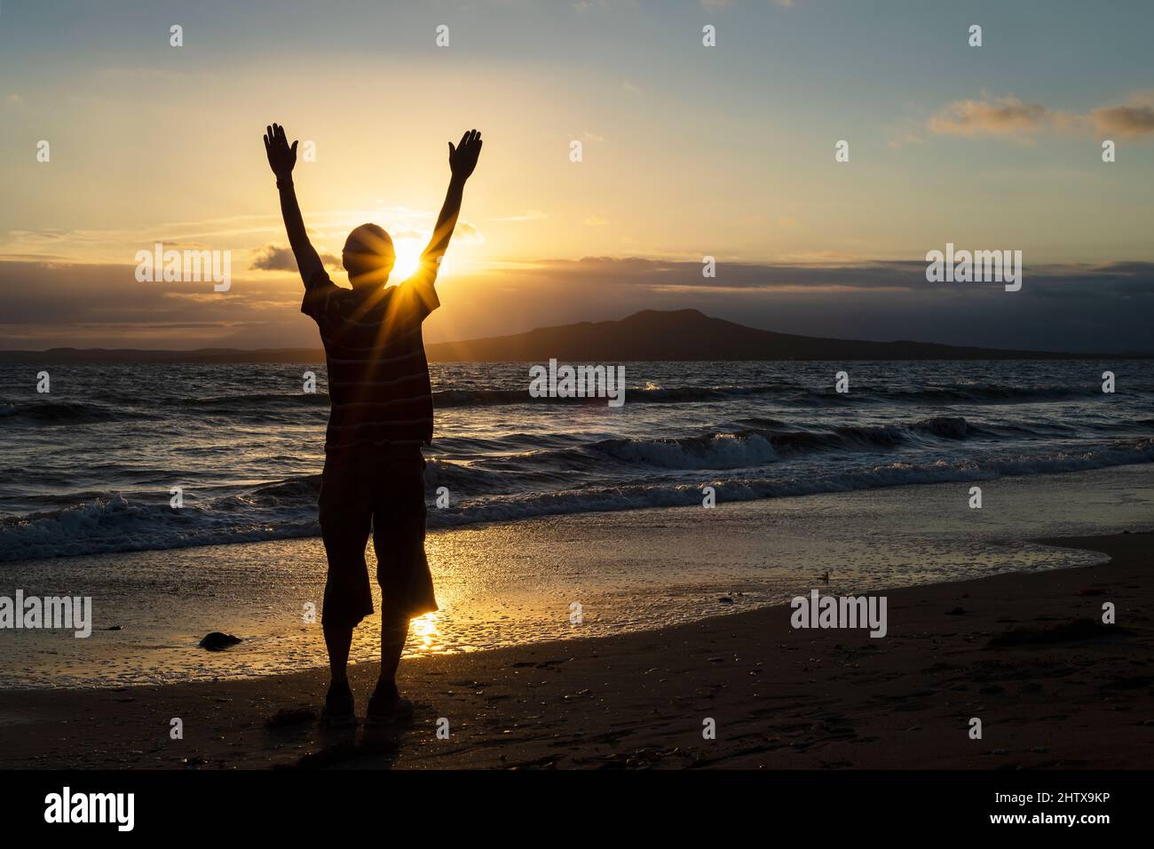Silhouette of a man with open arms greeting the sun rising over ...