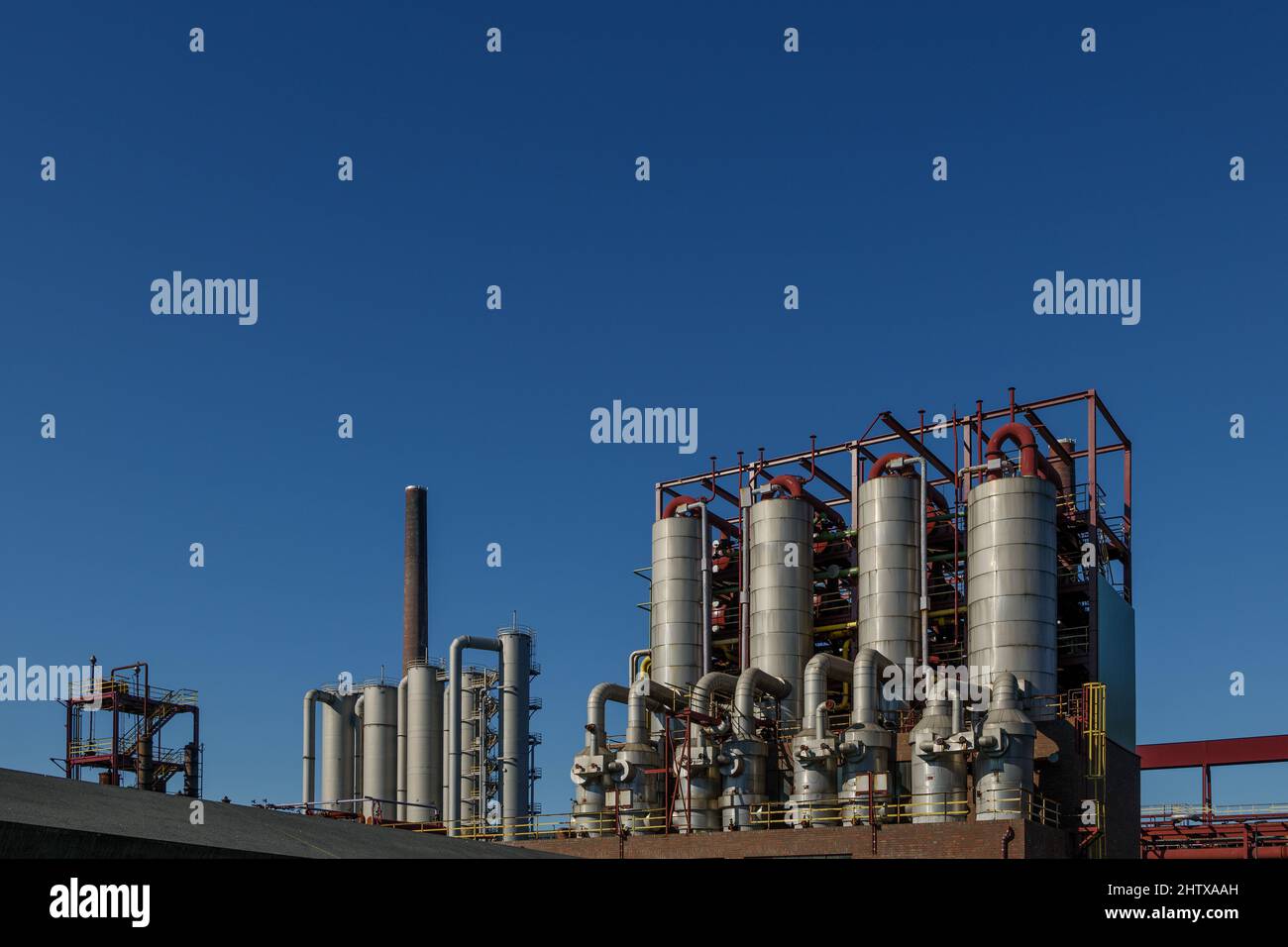 outdoor sunny view of high metal refinery tank, red painted structure ...