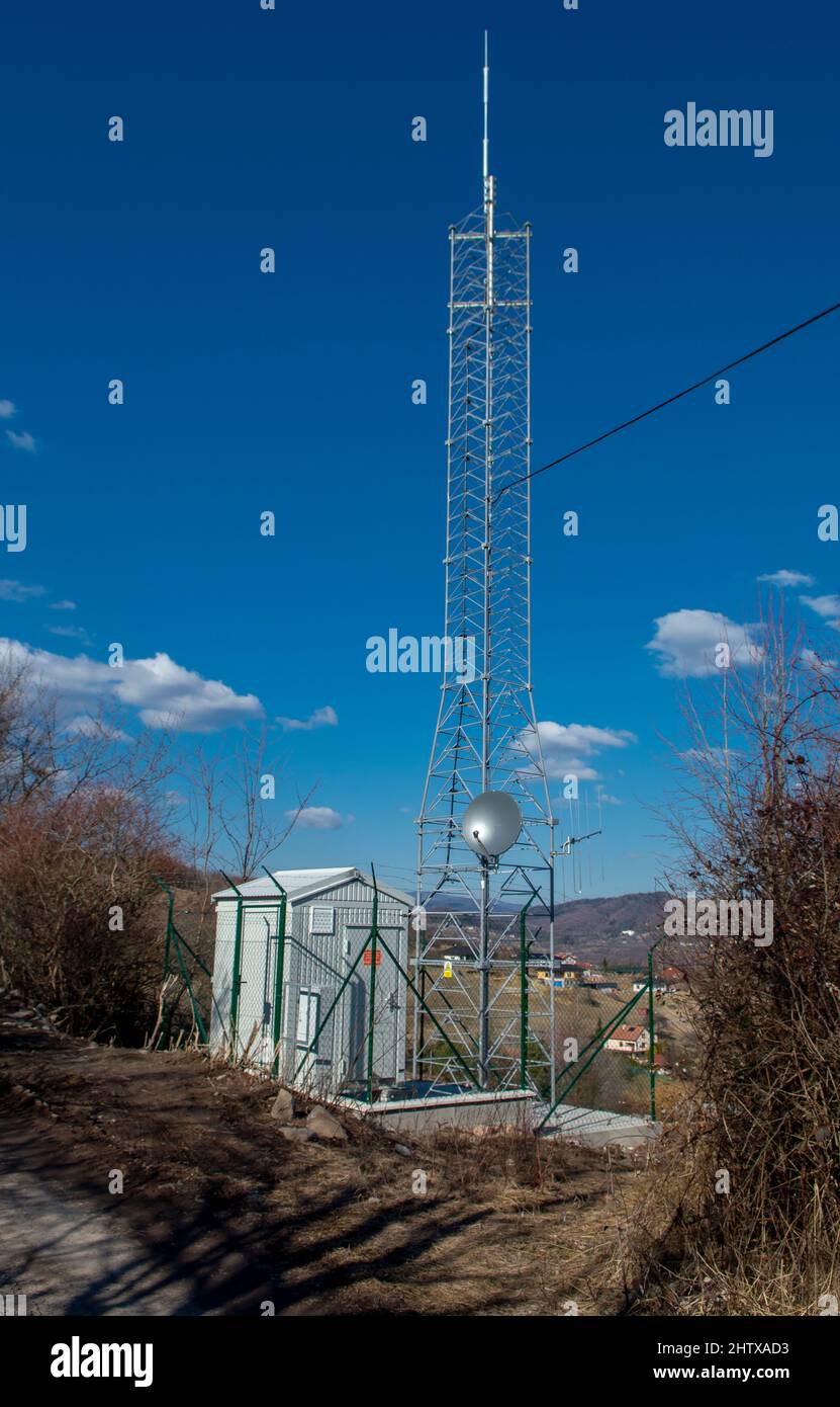 Mobile phone antenna tower in rural area against blue sky. Transmitter ...