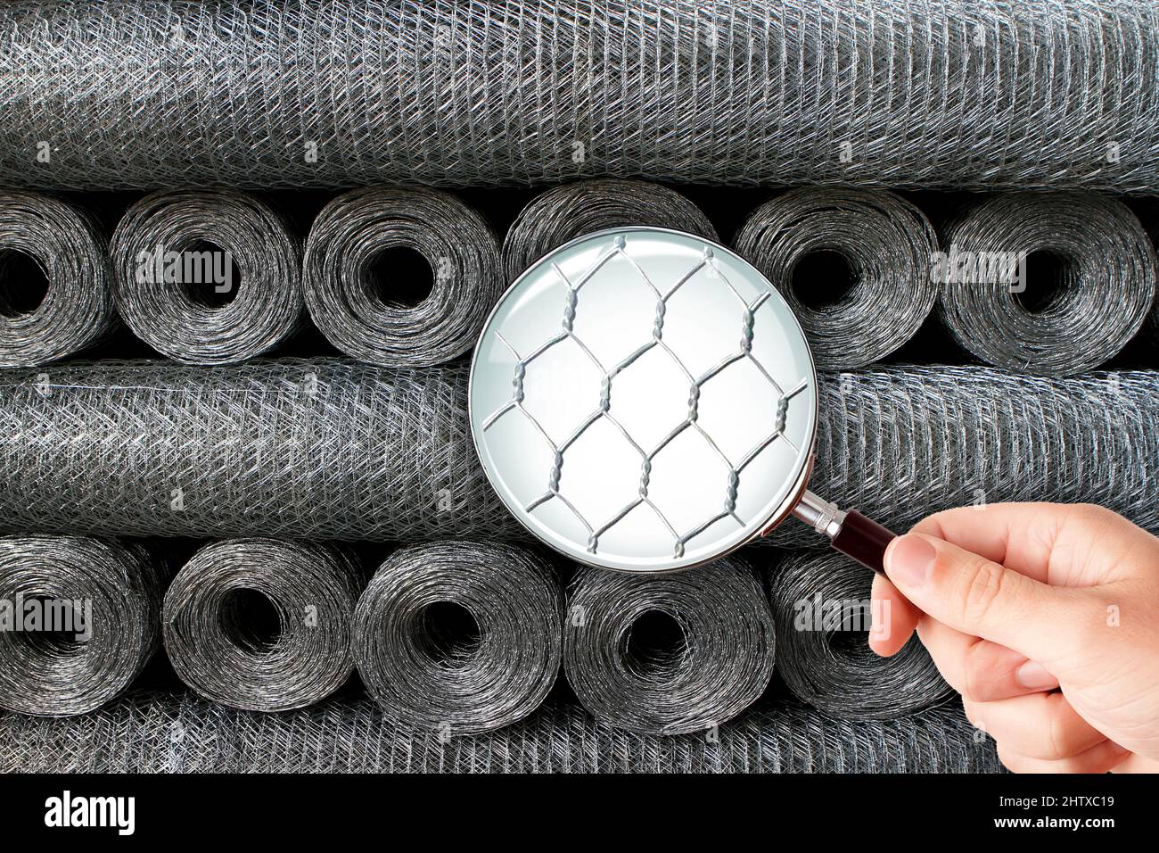 Man's hand with a magnifying glass looking on wire mesh Stock Photo - Alamy