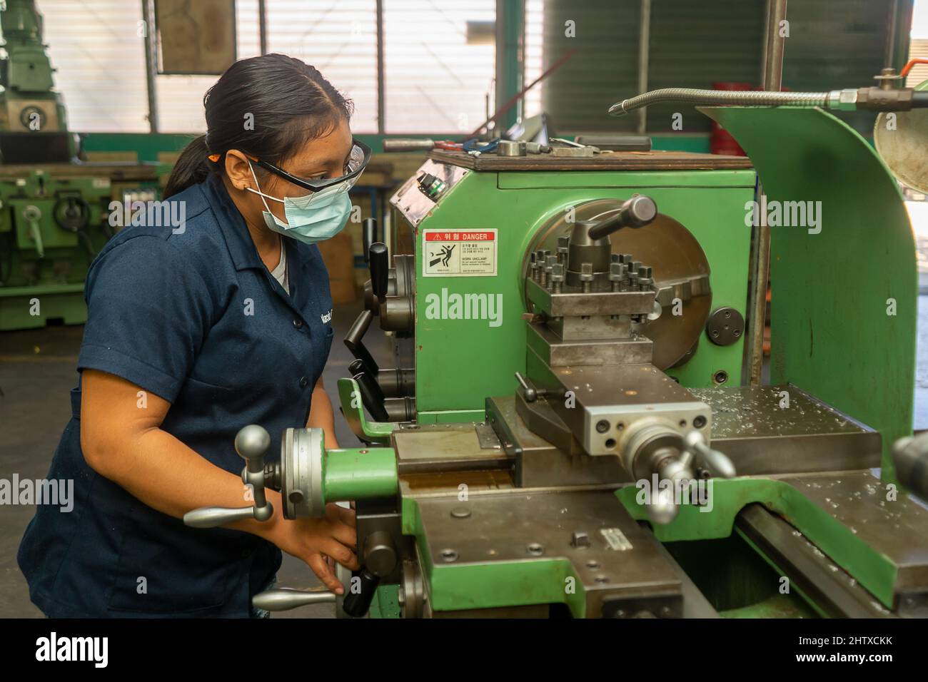 Latin young woman working on an industrial lathe as a symbol of female ...