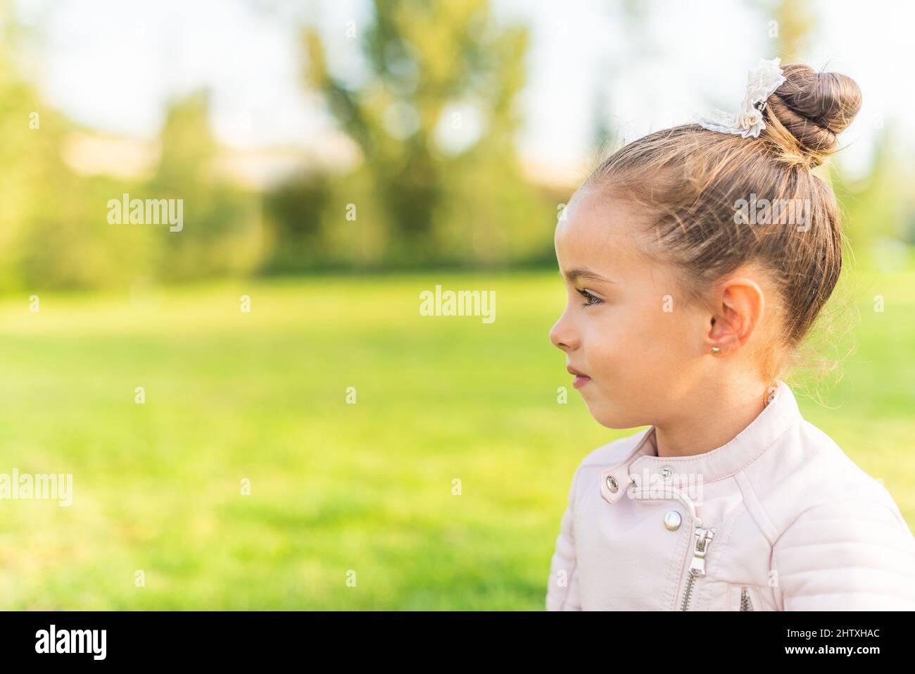 Side view of a little girl sitting on grass Stock Photo - Alamy