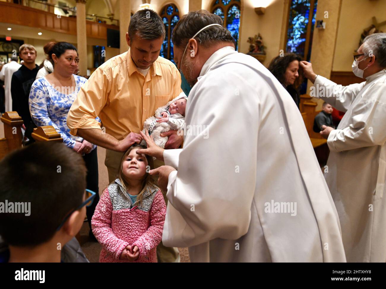A priest seen applying ash on a kid's forehead at Saints Peter and Paul ...