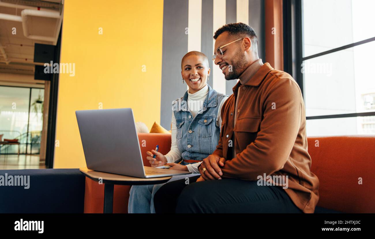 Colleagues working together in an office lobby. Two happy ...