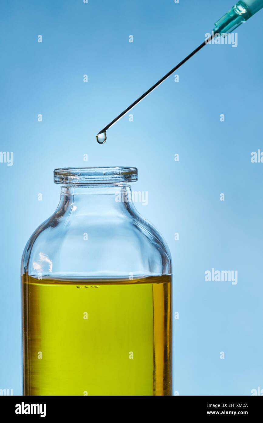 A drop of liquid drips from the needle of a medical syringe into the ...