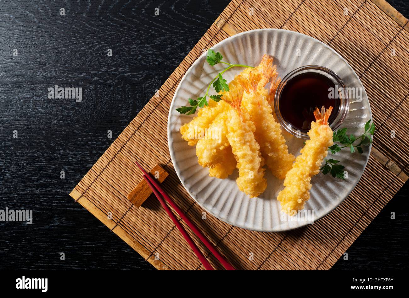 Shrimp tempura on a plate placed against a black background. Tempura is ...