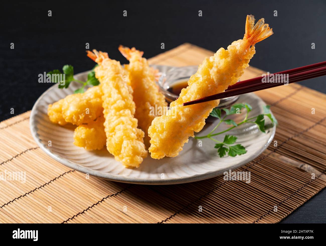 Shrimp tempura on a plate placed against a black background. Tempura is ...