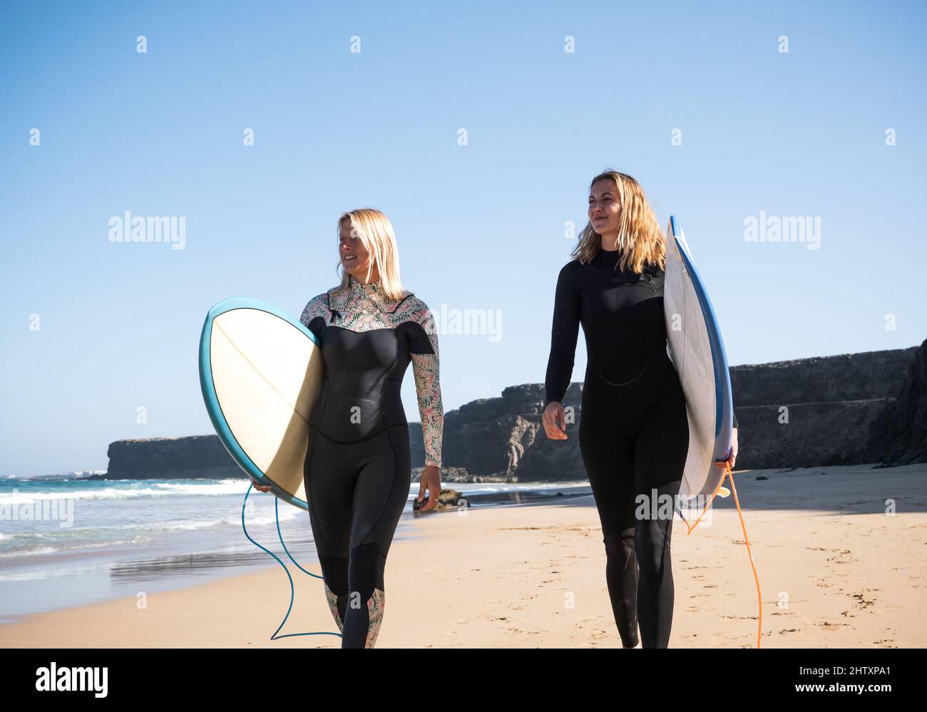 Caucasian surfer women on the beach looking to the waves. They are ...