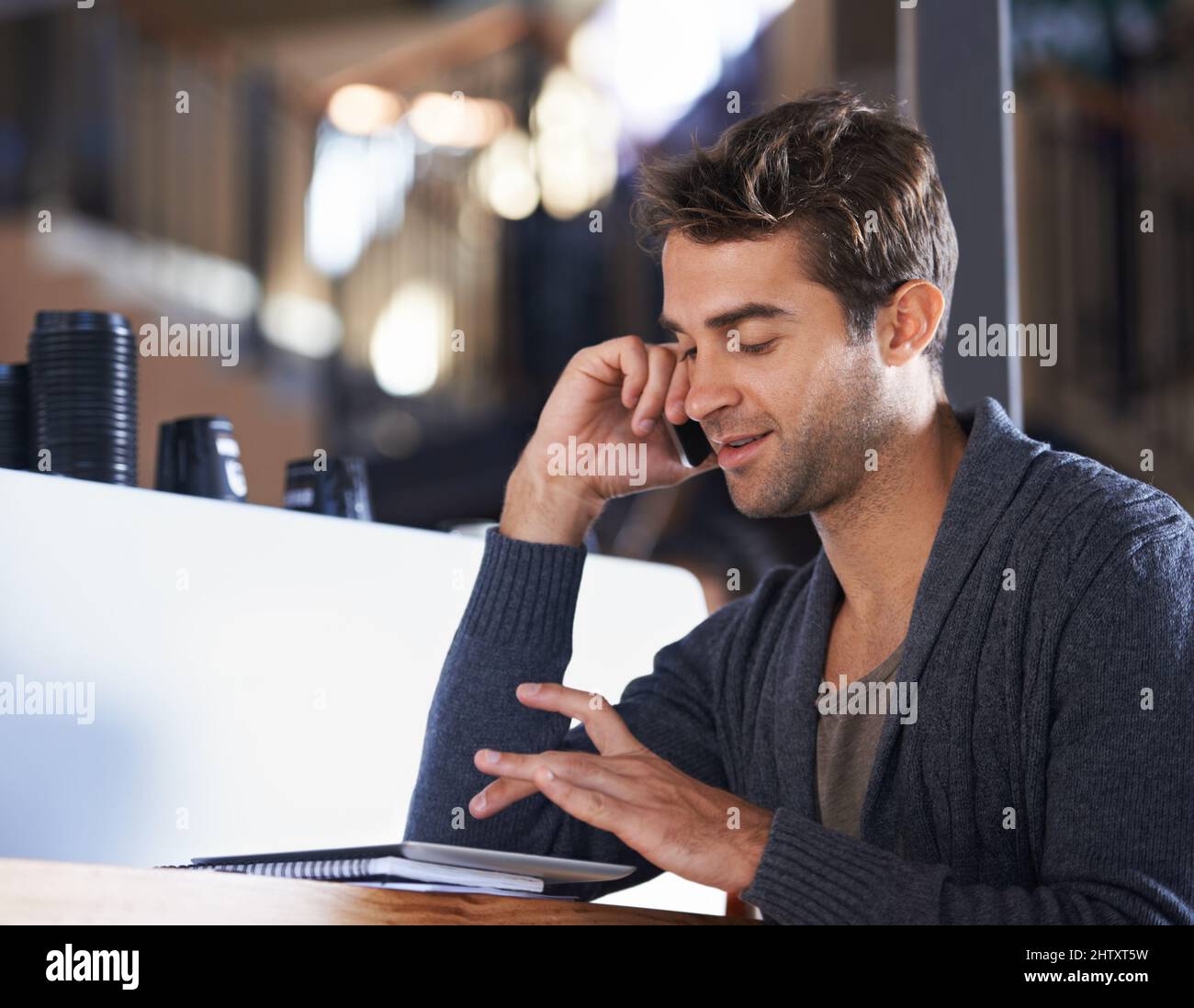 Phoning a friend for coffee. A young man sitting in a coffee shop ...