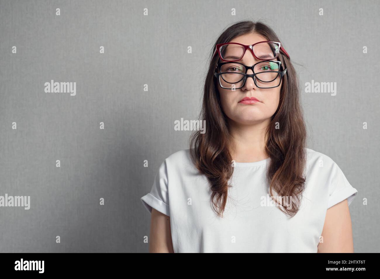 woman with a sad face in three glasses stands against the background of ...