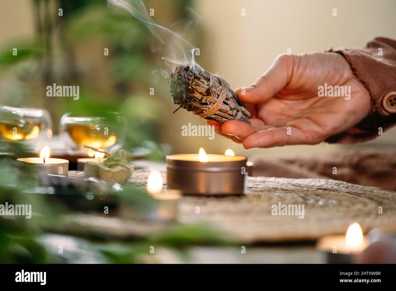 Woman hands burning white sage, before ritual on the table with candles ...