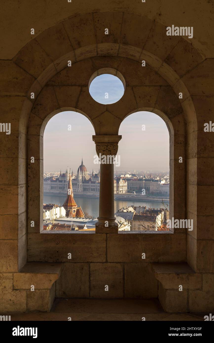 View through an arched window of the Fishermen's Bastion onto the Danube with the Parliament ...