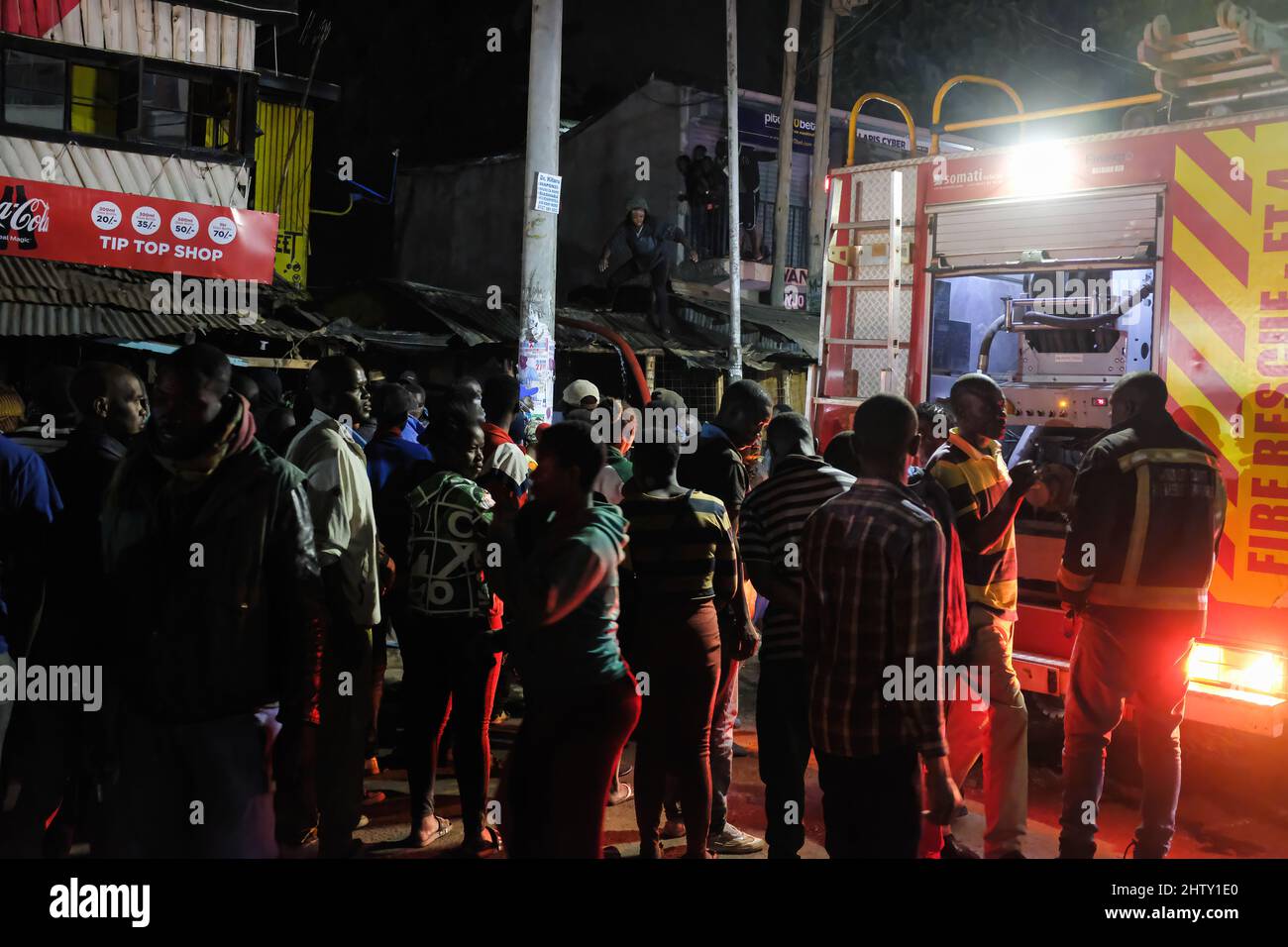 Residents watch from a distance as firefighters struggle to put out a ...