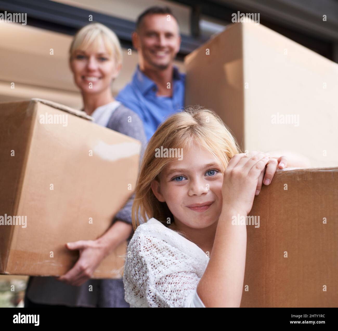 Were going to our new house. A family of three carrying boxes into ...
