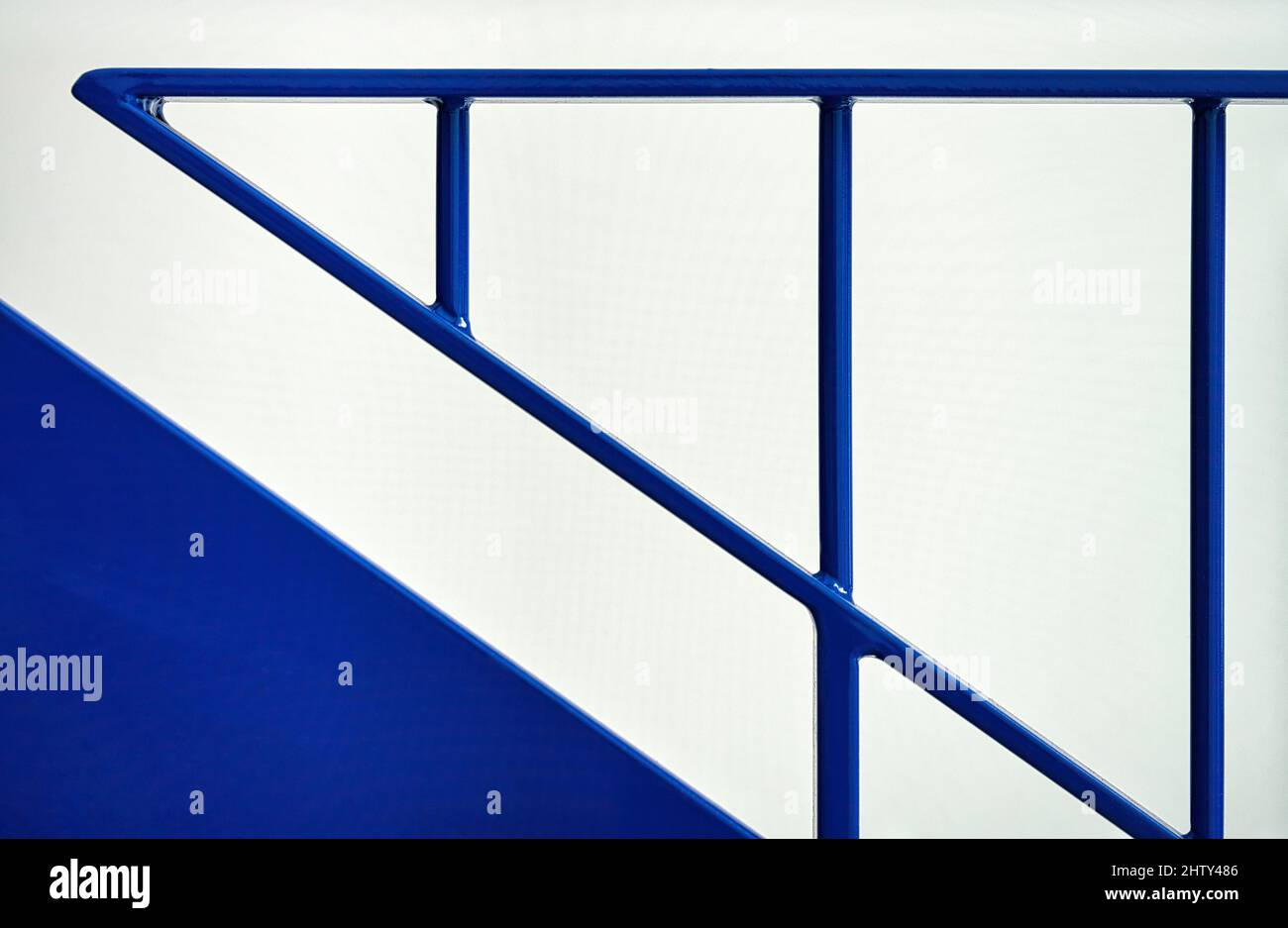 Blue stair railing, geometric abstract form, in front of white wall ...