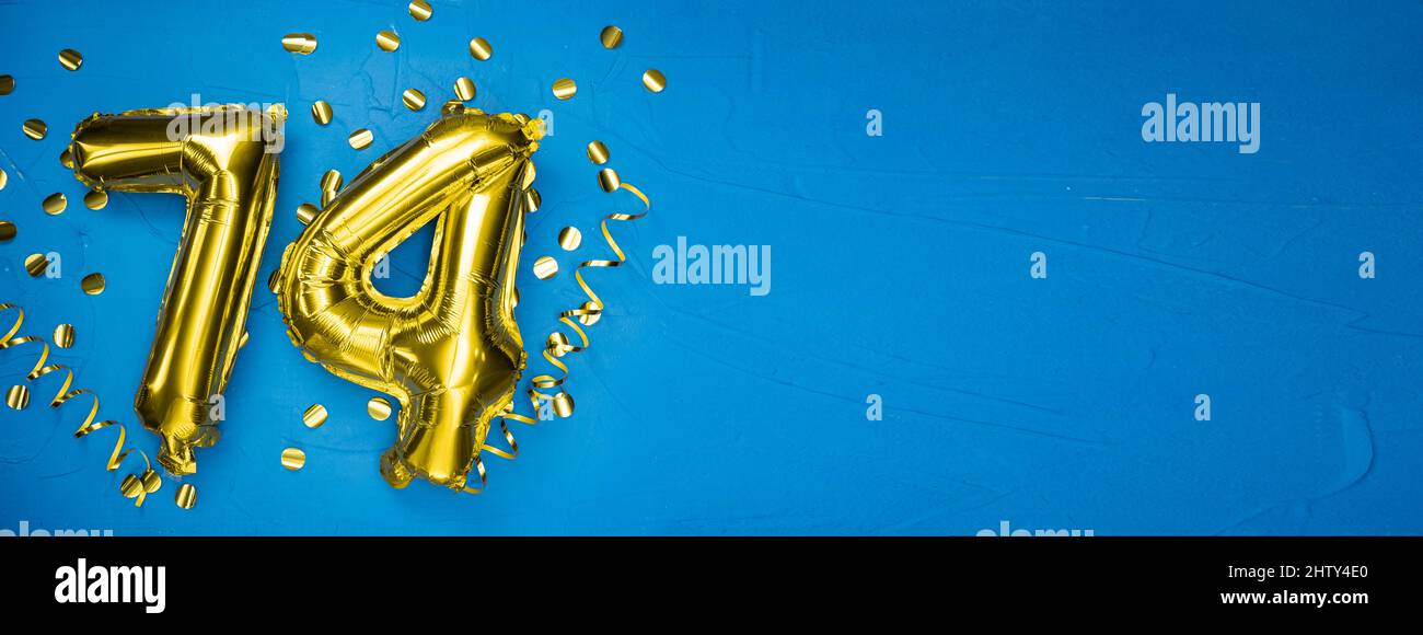 golden yellow foil balloon on blue concrete background number seventy ...