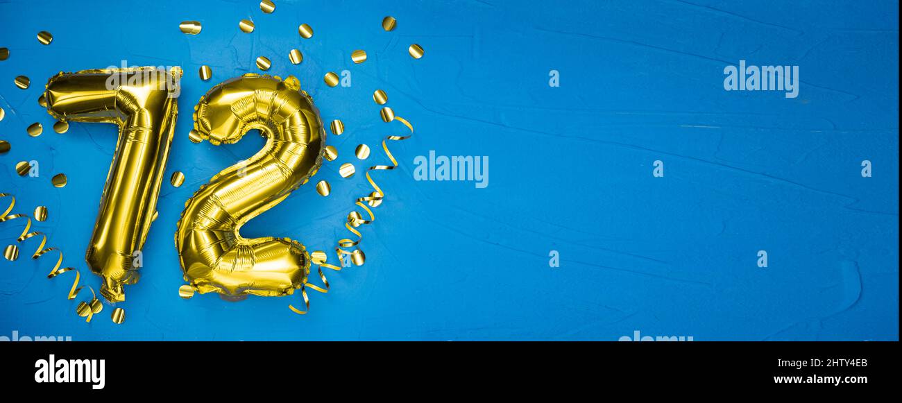 golden yellow foil balloon on blue concrete background number seventy ...