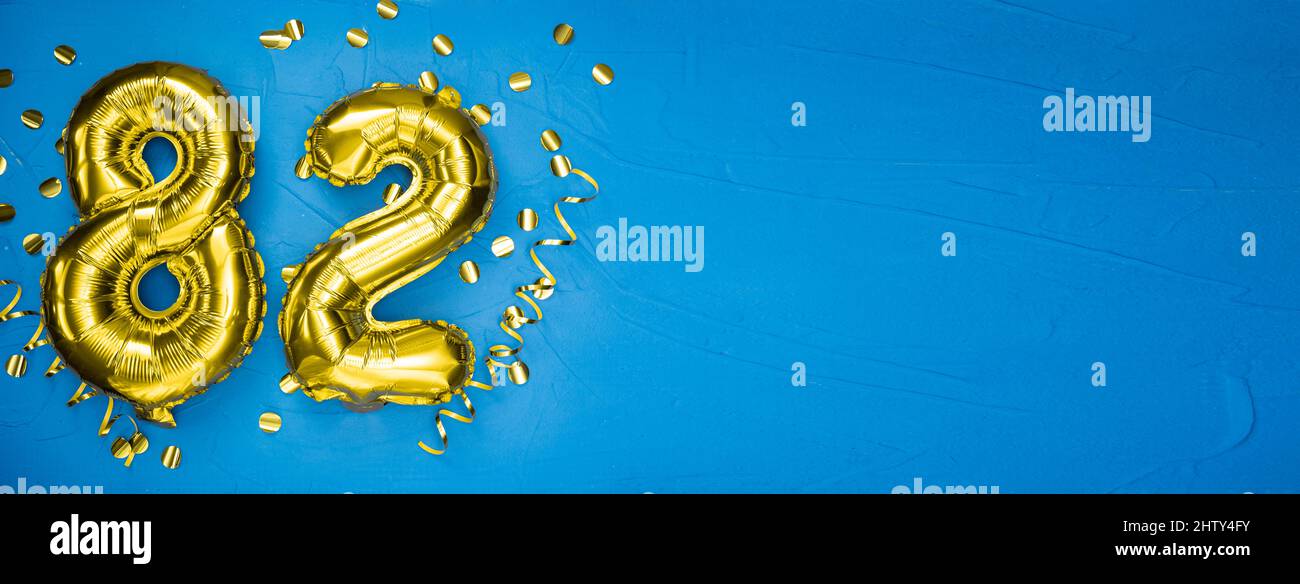 golden yellow foil balloon on blue concrete background number eighty ...